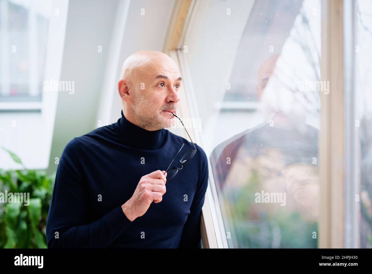 Thinking man standing at the window and looking out Stock Photo - Alamy