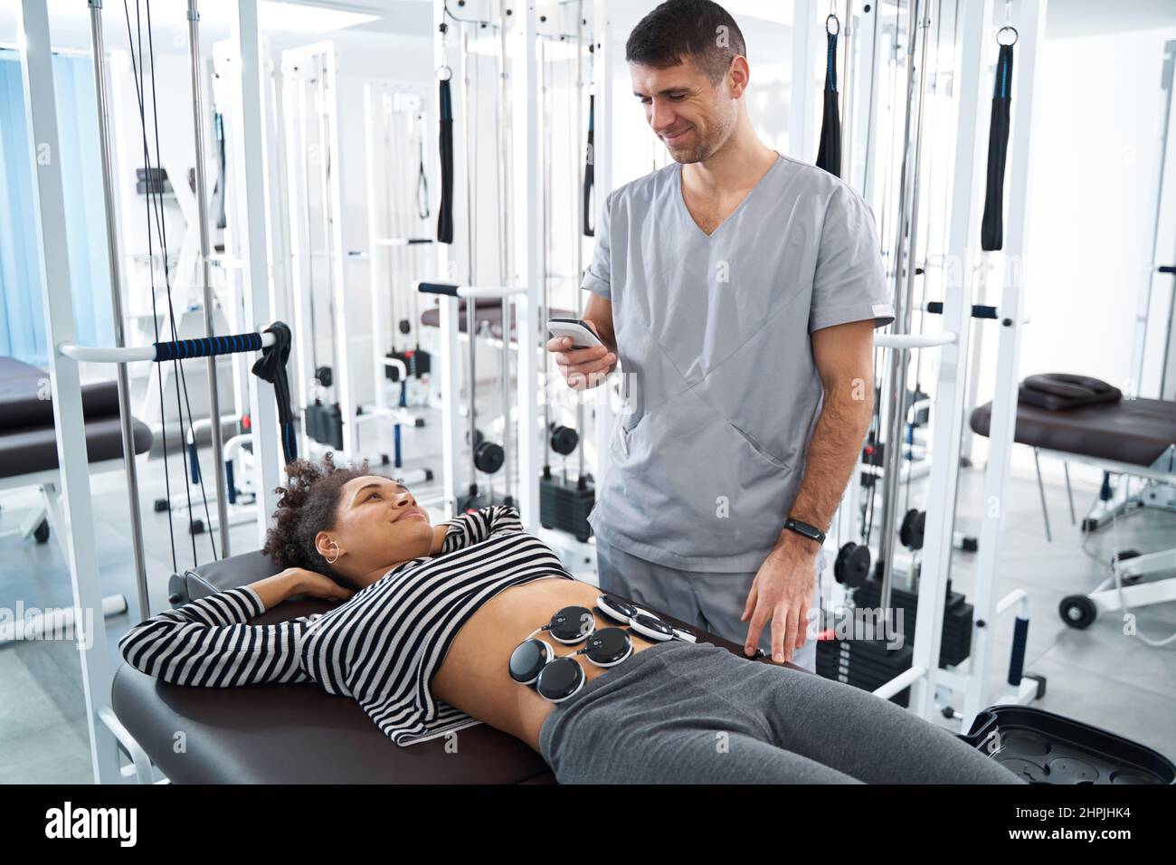 Medical worker helping young lady having rehabilitation Stock Photo - Alamy