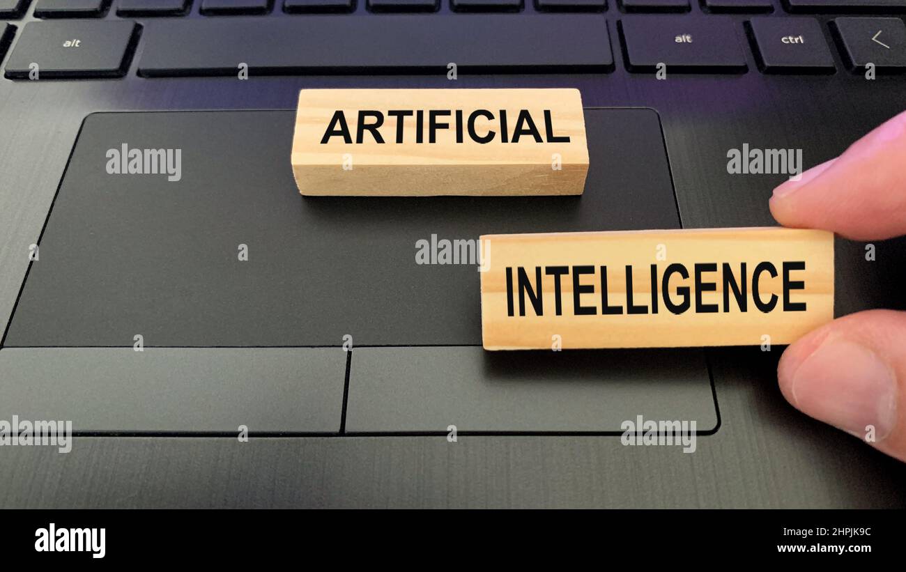 Artificial intelligence text on wooden blocks with laptop background ...