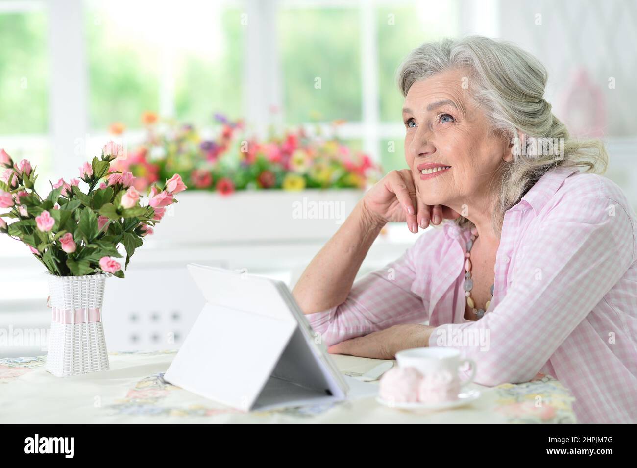 Beautiful senior woman using modern tablet while drinking tea Stock ...