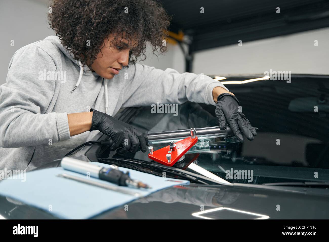 Mechanic using ultraviolet light during windshield repair Stock Photo ...