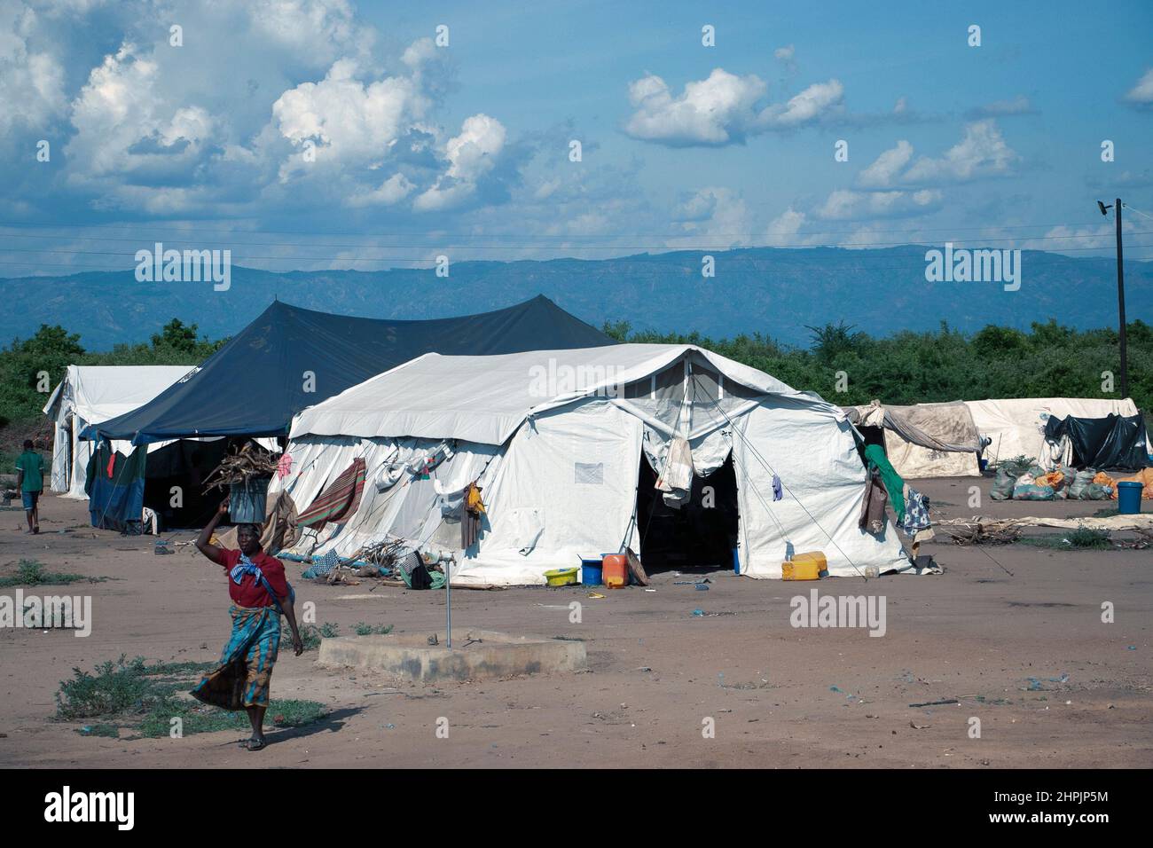 A woman is seen carrying firewood at a temporary shelter for people ...
