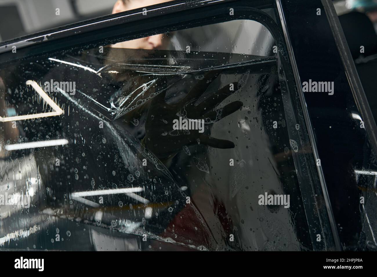 Skilled mechanic installing protection film on windshield Stock Photo ...