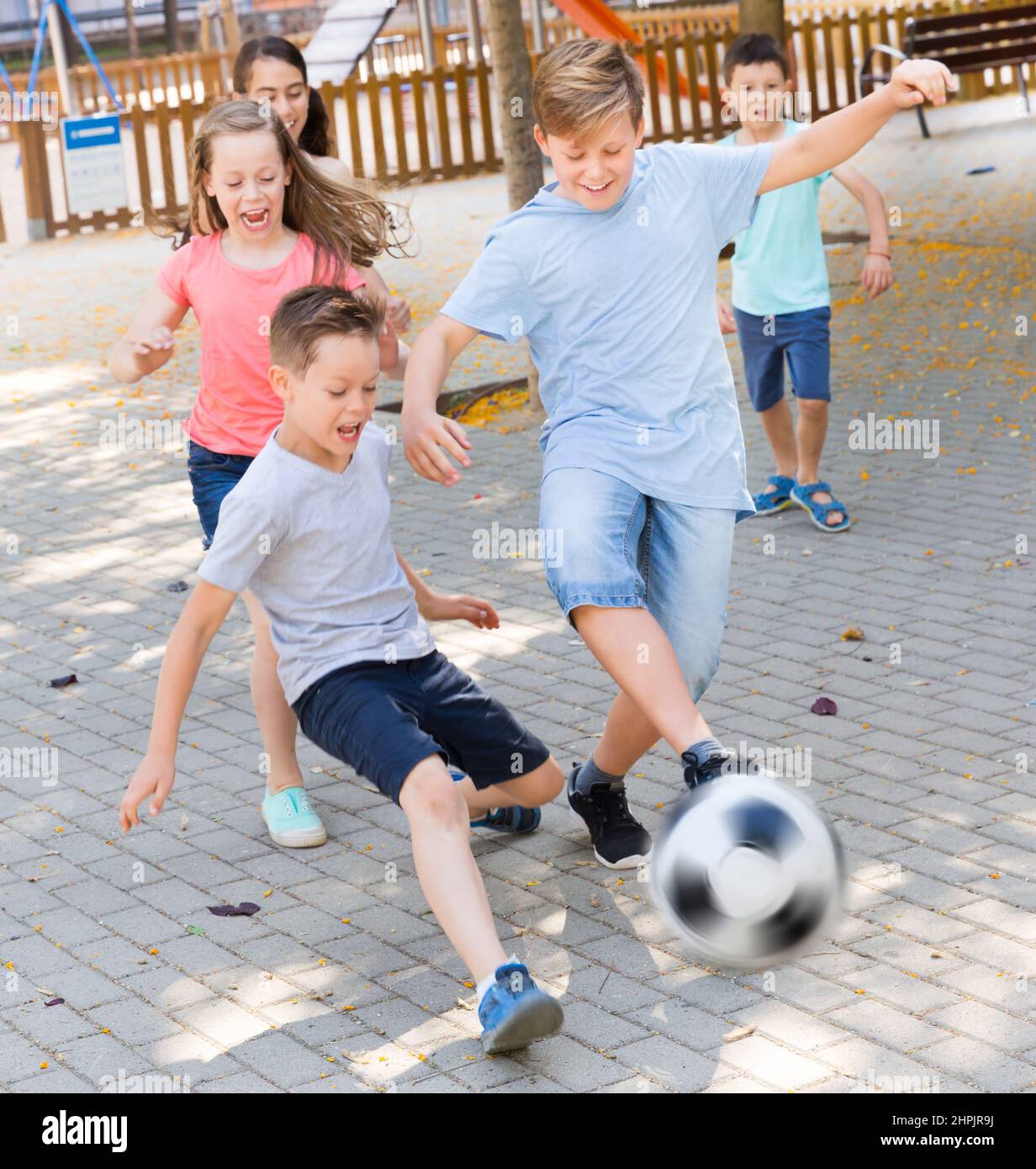Happy children playfully running after ball Stock Photo - Alamy