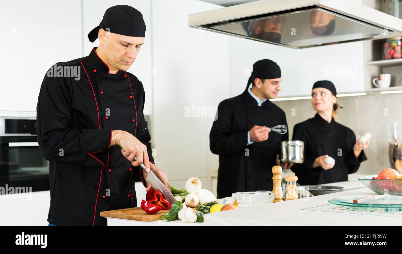 Female and male cooks wearing black uniform working on kitchen Stock ...