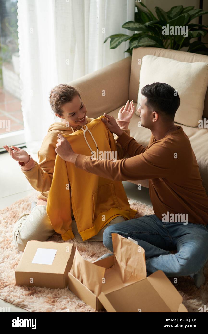 Young man unpacking the box with new sweater and giving it to his ...