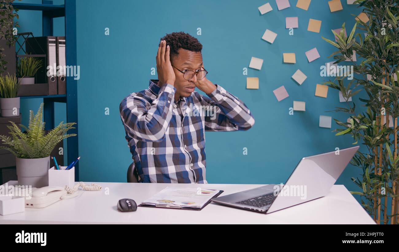 Amazed worker doing three wise monkeys symbol at desk, using laptop ...