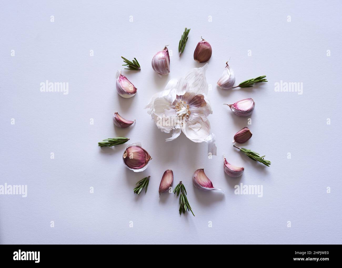 A circular explosion of garlic and herbs on white background. Flat lay ...
