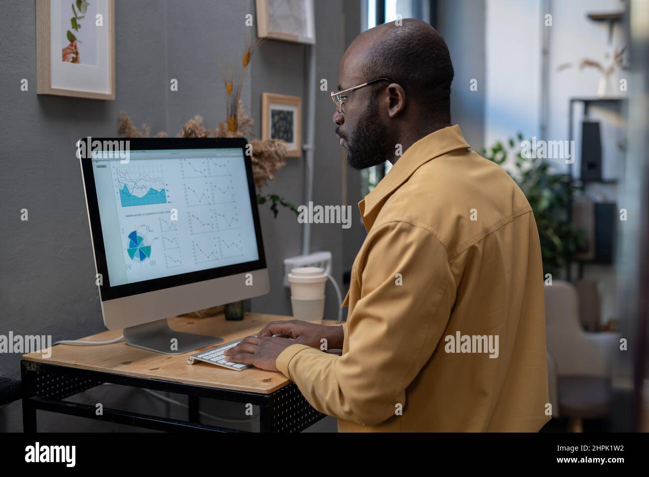 Modern African-American businessman sitting by desk in front of ...