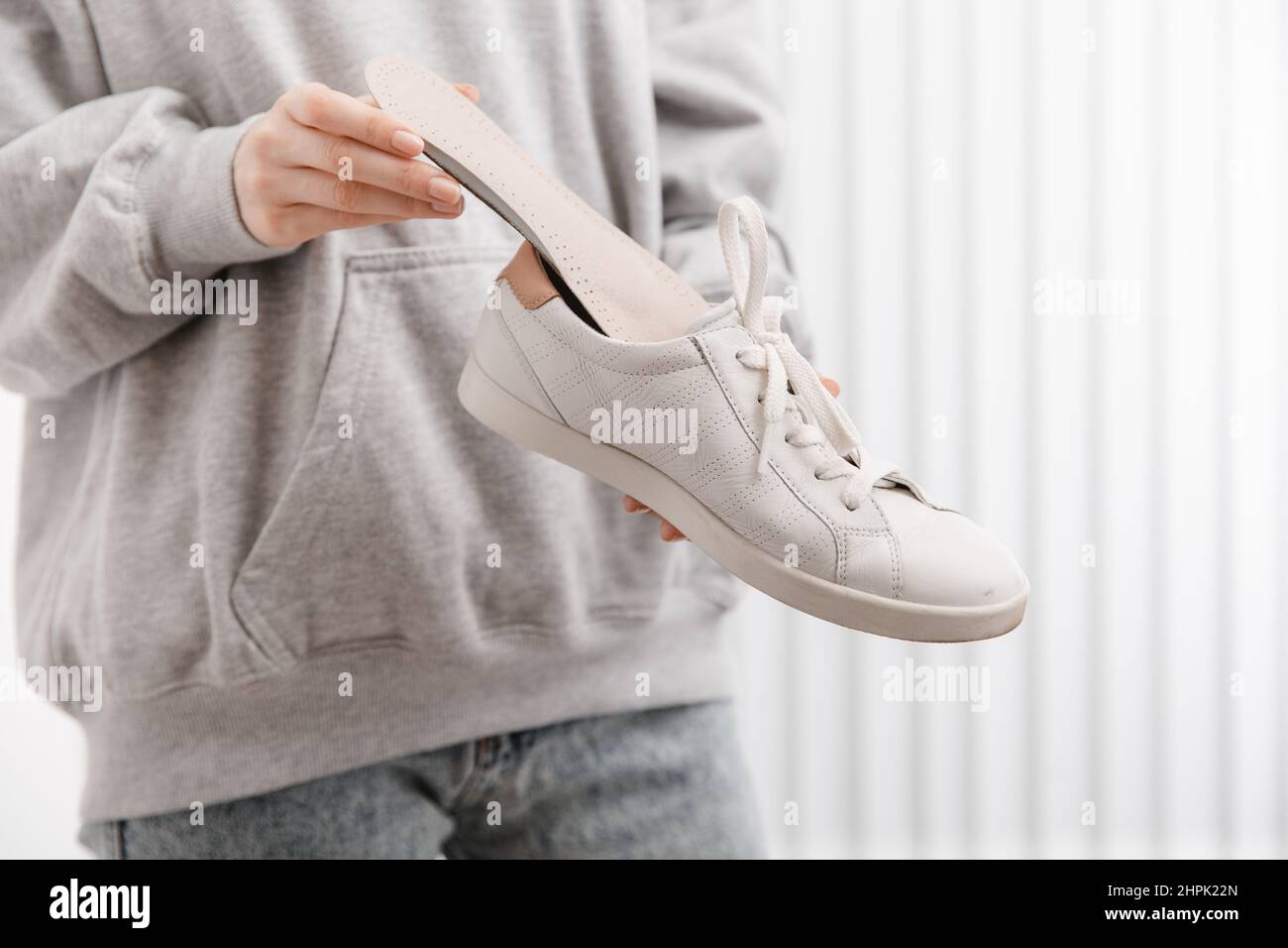 Woman putting orthopedic insole into shoe at home. Sports girl fitting ...