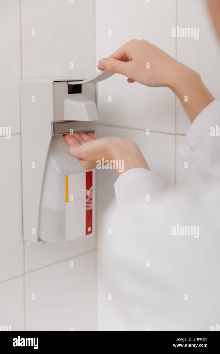 The doctor in white uniform disinfects his hands. Surgeon washing hands ...