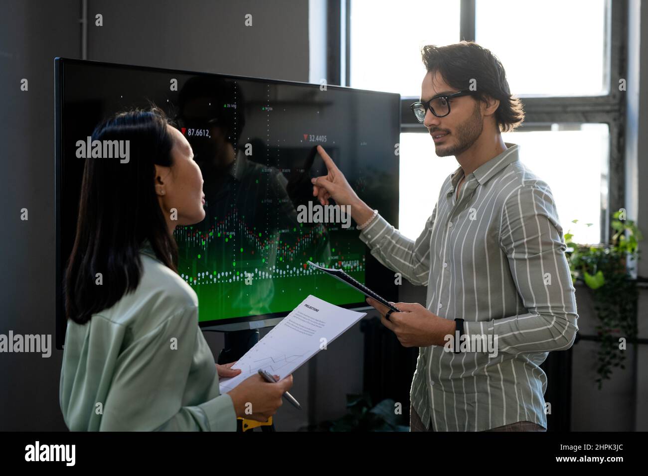 Young confident analyst pointing at digital financial data on ...