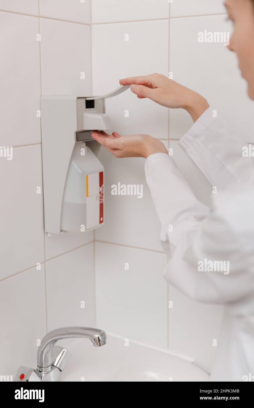 The doctor in white uniform disinfects his hands. Surgeon washing hands ...