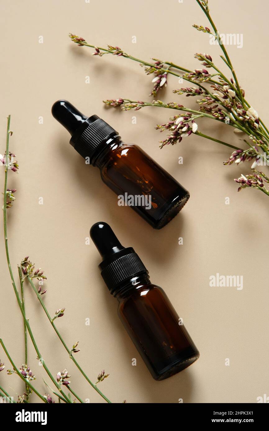 Essential oil amber glass dropper bottles with flowers on beige ...