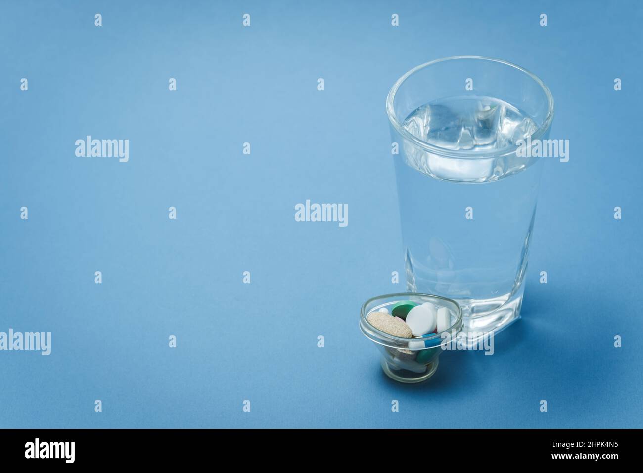 Medical concept - A glass of water and medicines on a blue background ...