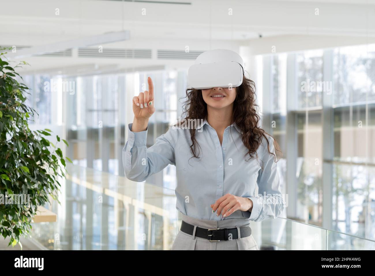 Happy young contemporary gaming developer in vr headset pointing at ...