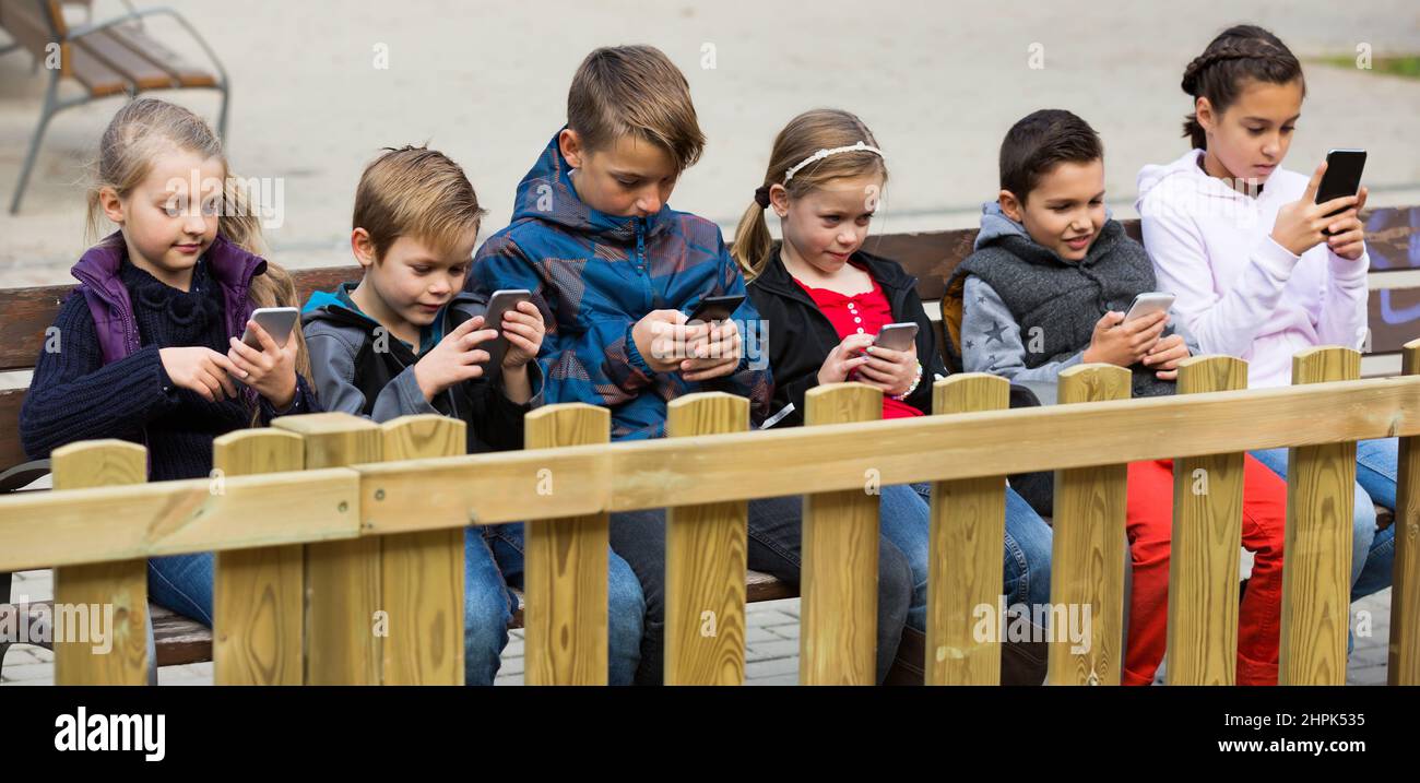 Children sit on bench in street Stock Photo - Alamy