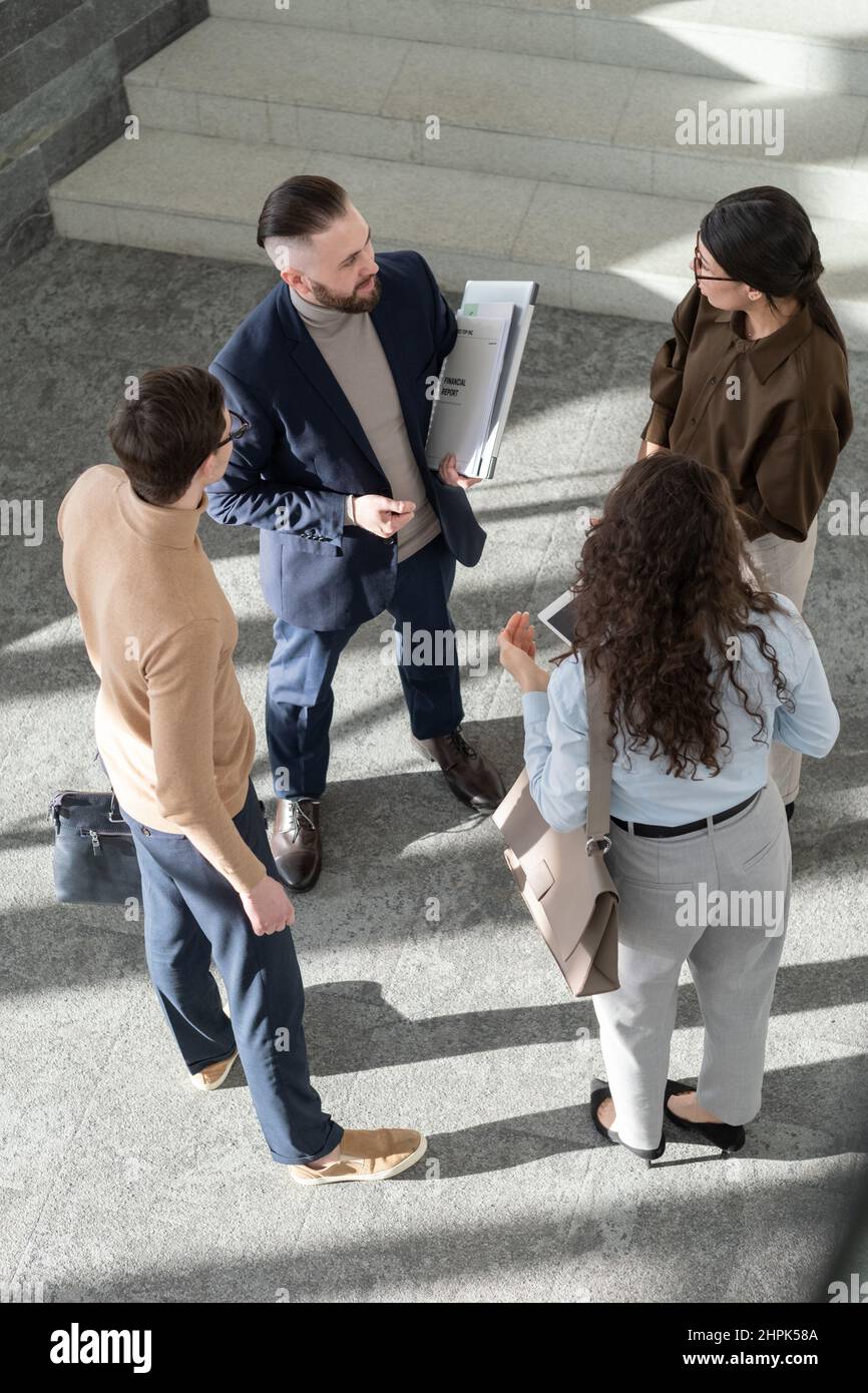 Young coworkers in formalwear standing inside large office center and ...