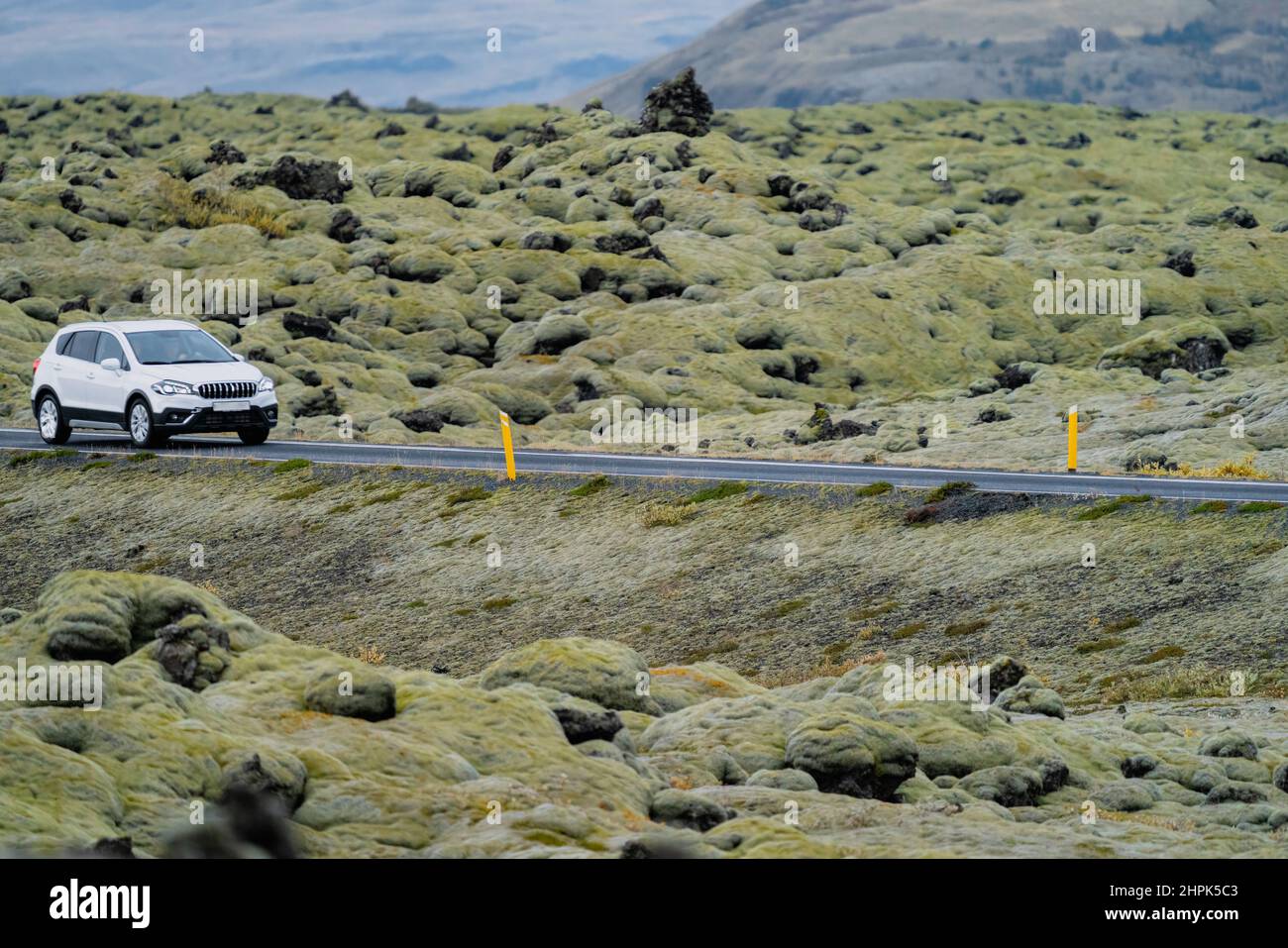 White car driving through lava fields covered by moss Stock Photo - Alamy