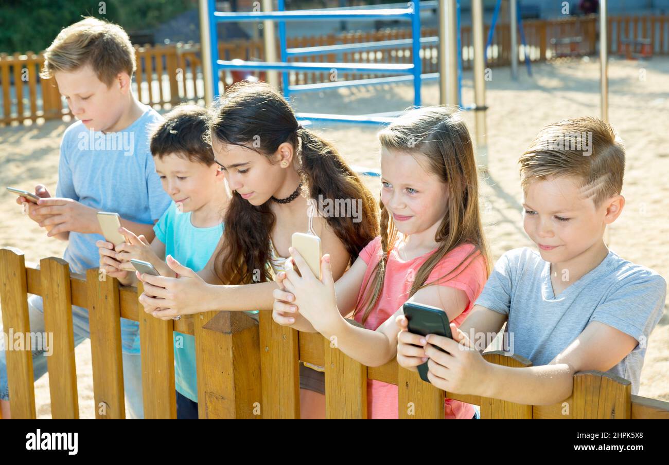 Five children sitting and playing in smartphone Stock Photo - Alamy