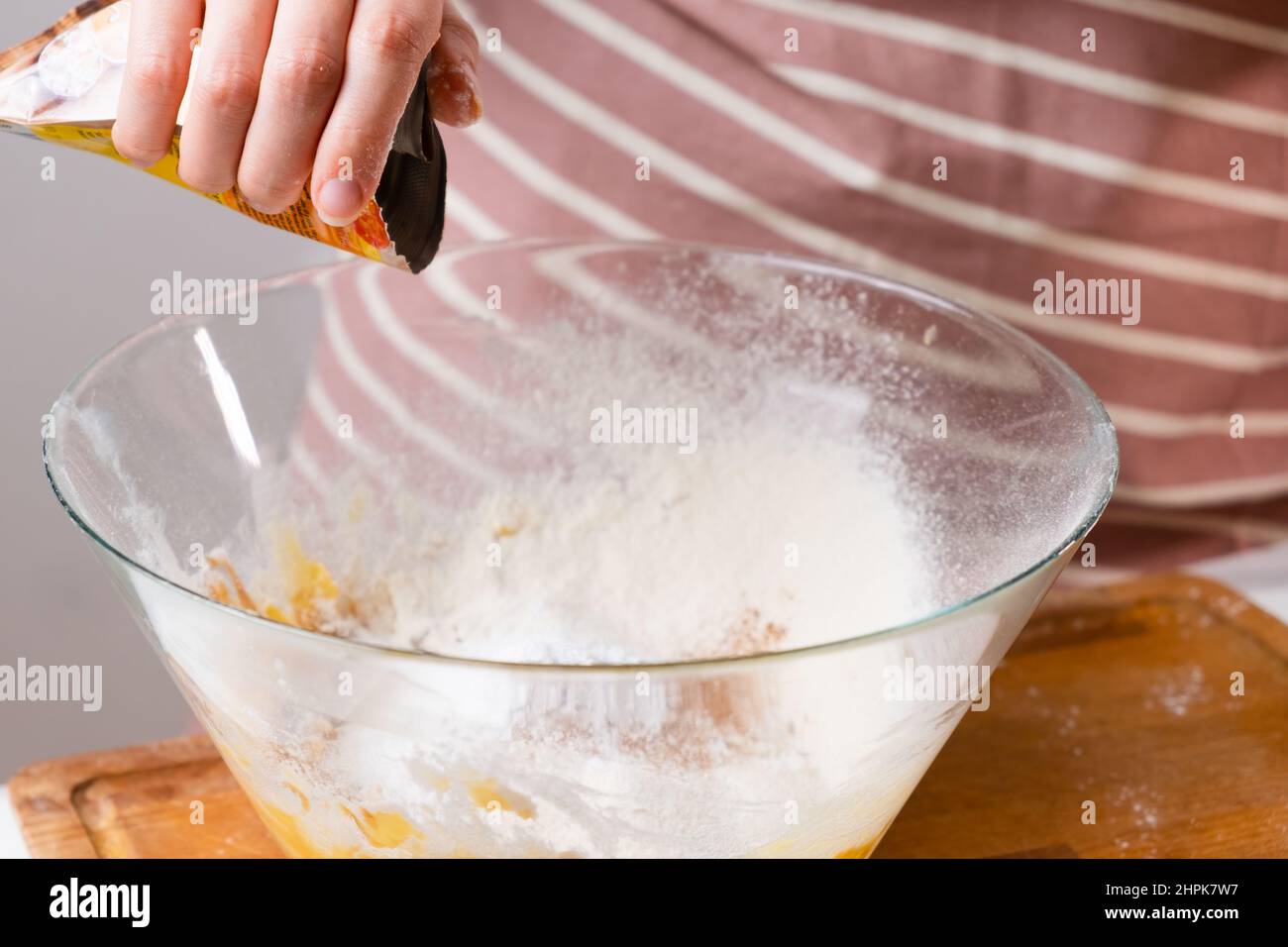 Close up woman sifts wheat flour through a sieve into mixing bowl for ...