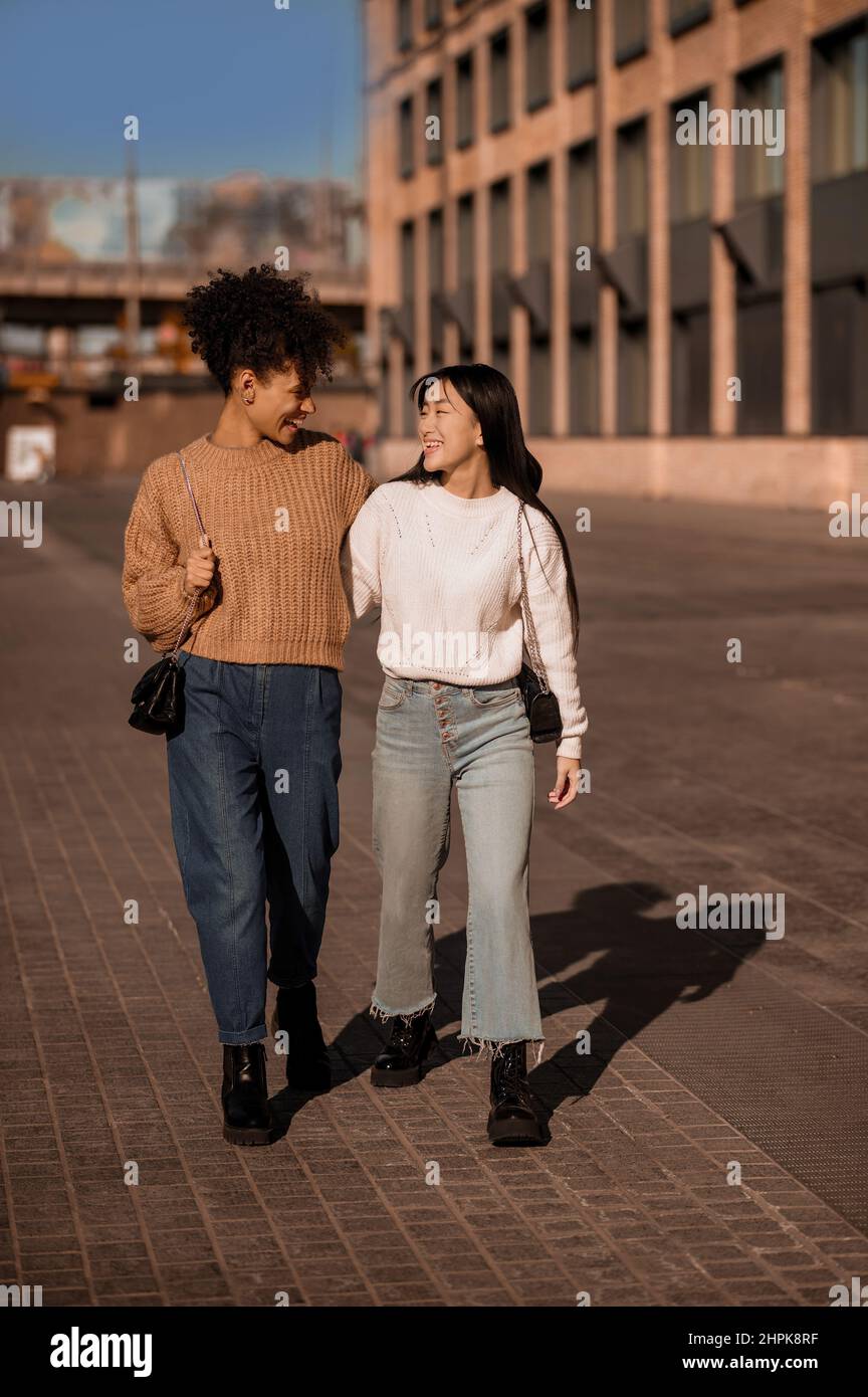 Two pretty girls walking and talking, feeling joyful Stock Photo - Alamy