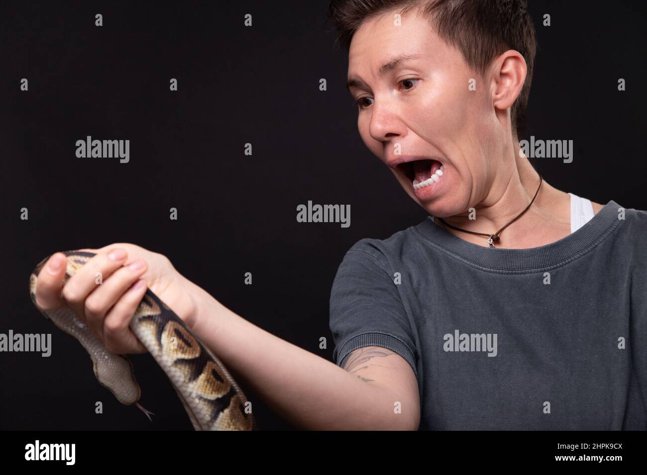 Photo of scared woman with python on black background Stock Photo - Alamy