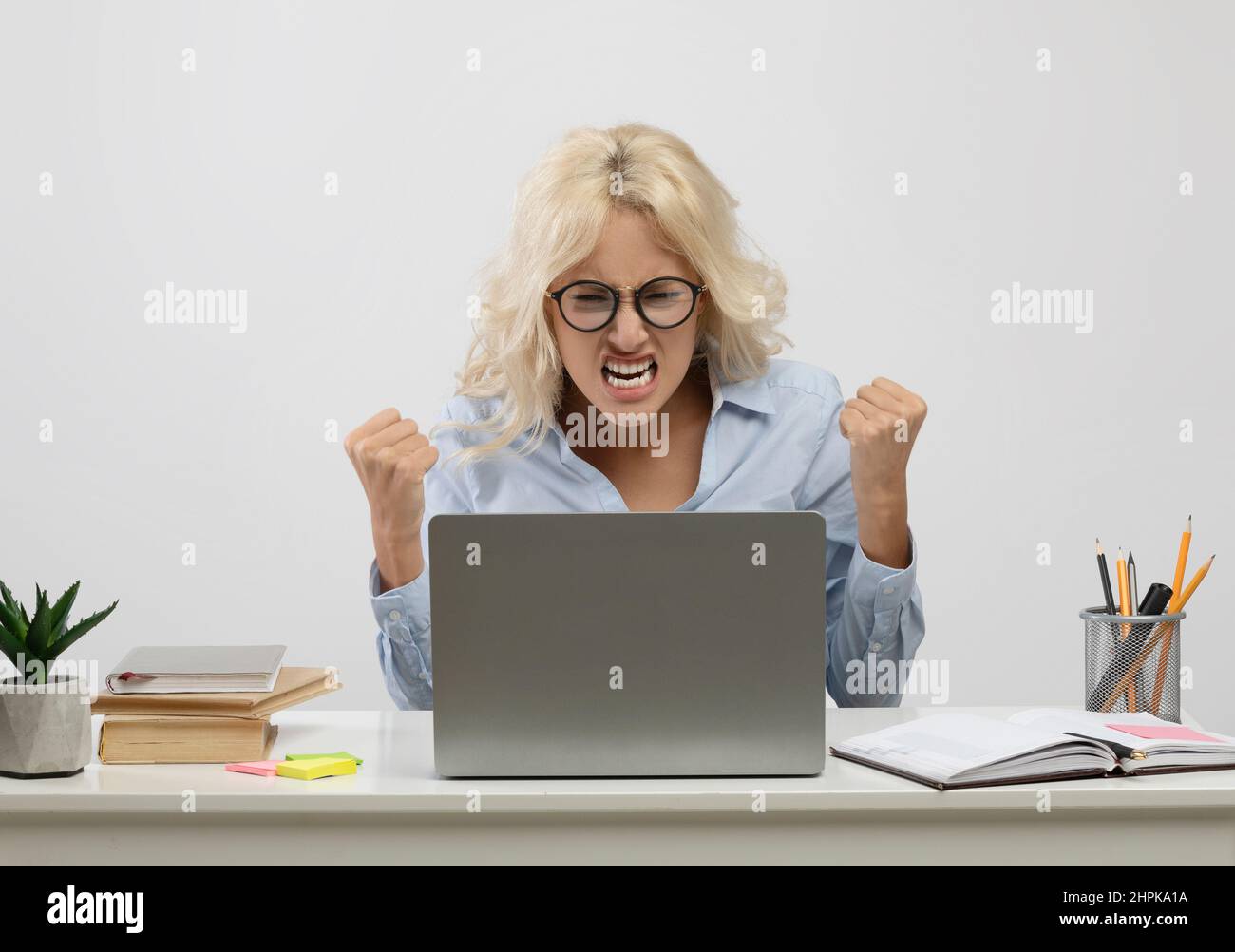 Frustrated female office worker sitting at desk with laptop and getting ...