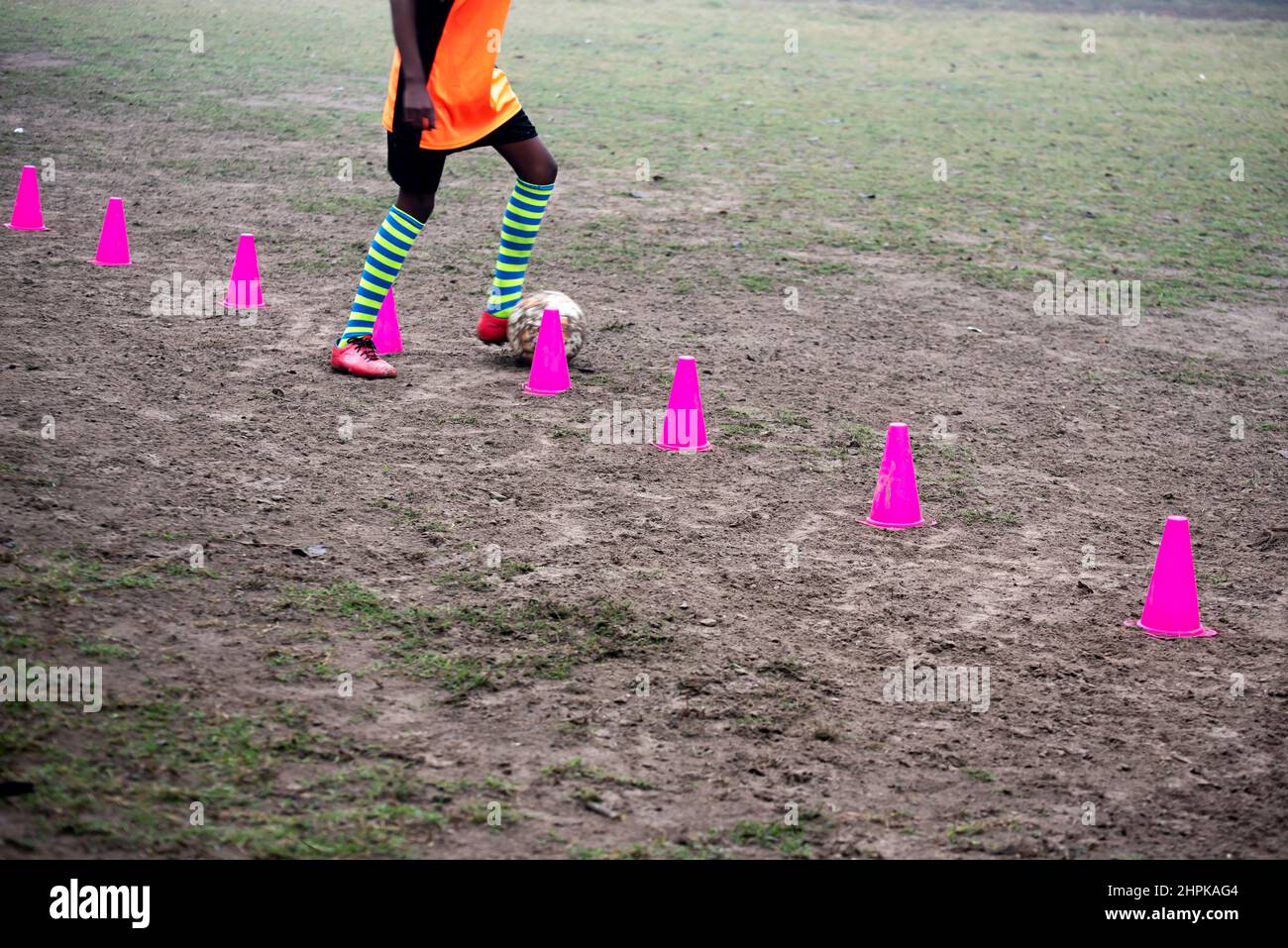 Footballer dribbling ball during training between cones. Young soccer ...