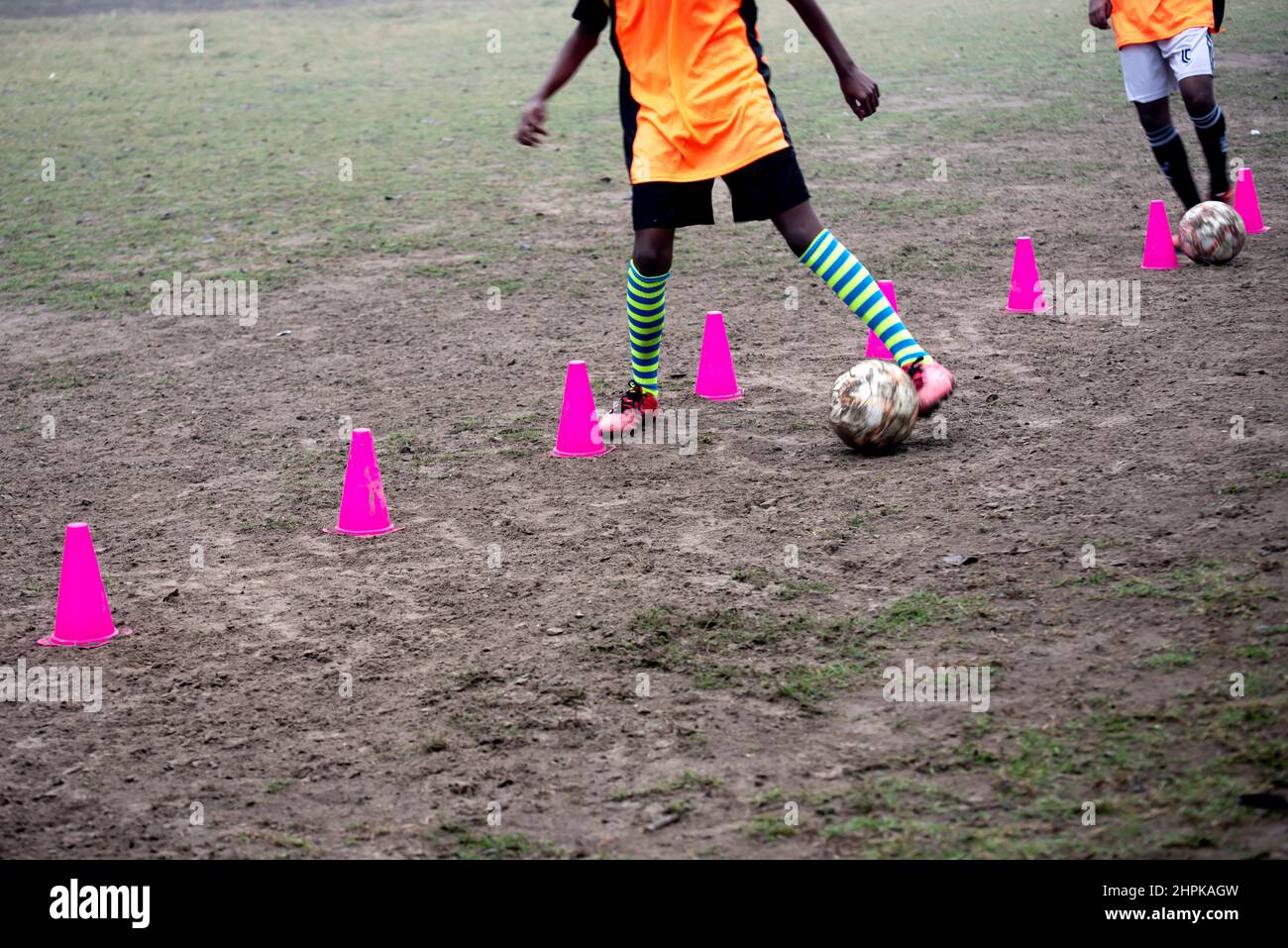 Footballer dribbling ball during training between cones. Young soccer ...