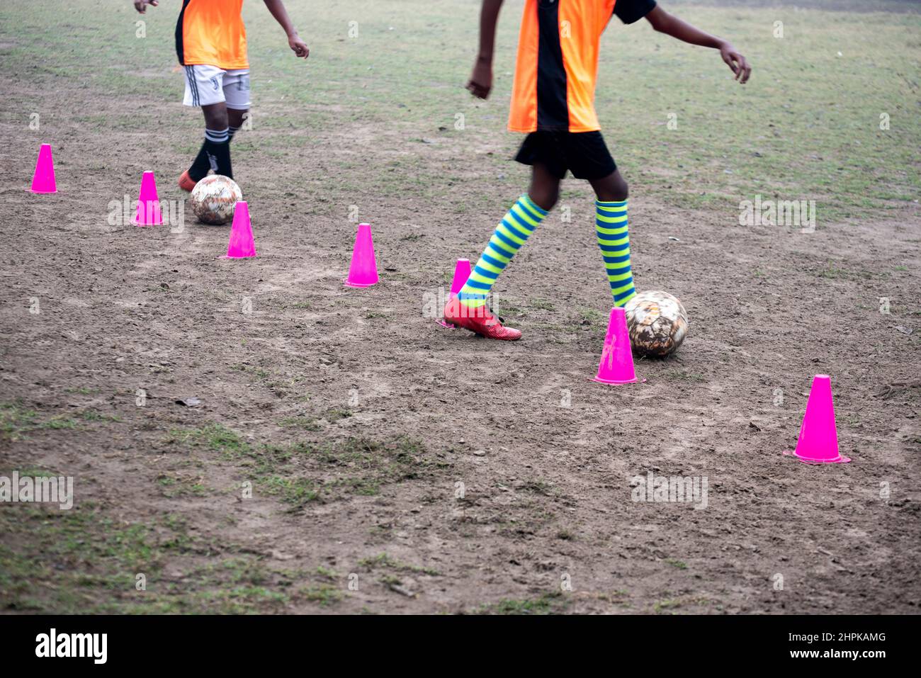 Footballer dribbling ball during training between cones. Young soccer ...