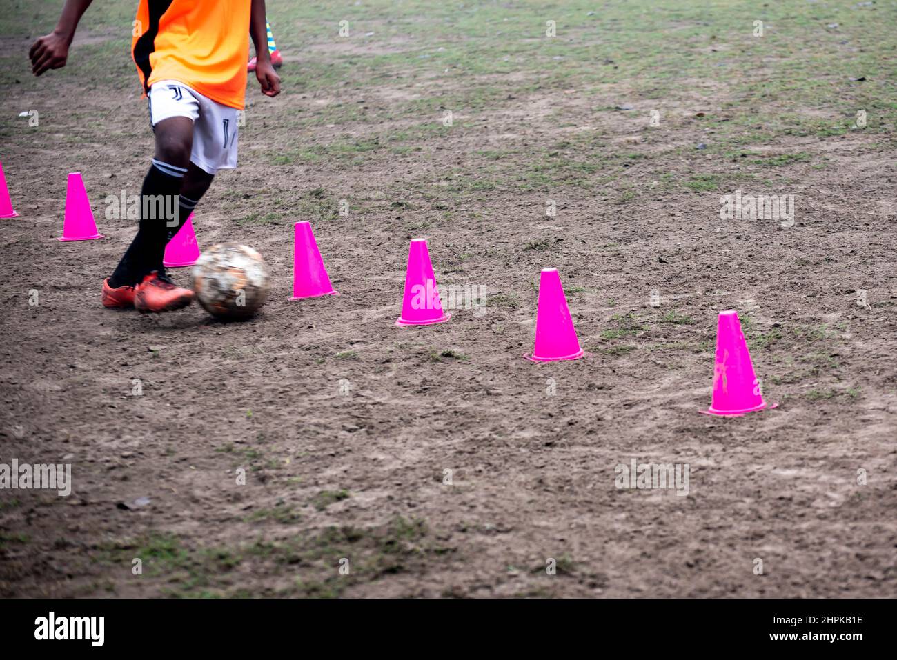 Footballer dribbling ball during training between cones. Young soccer ...