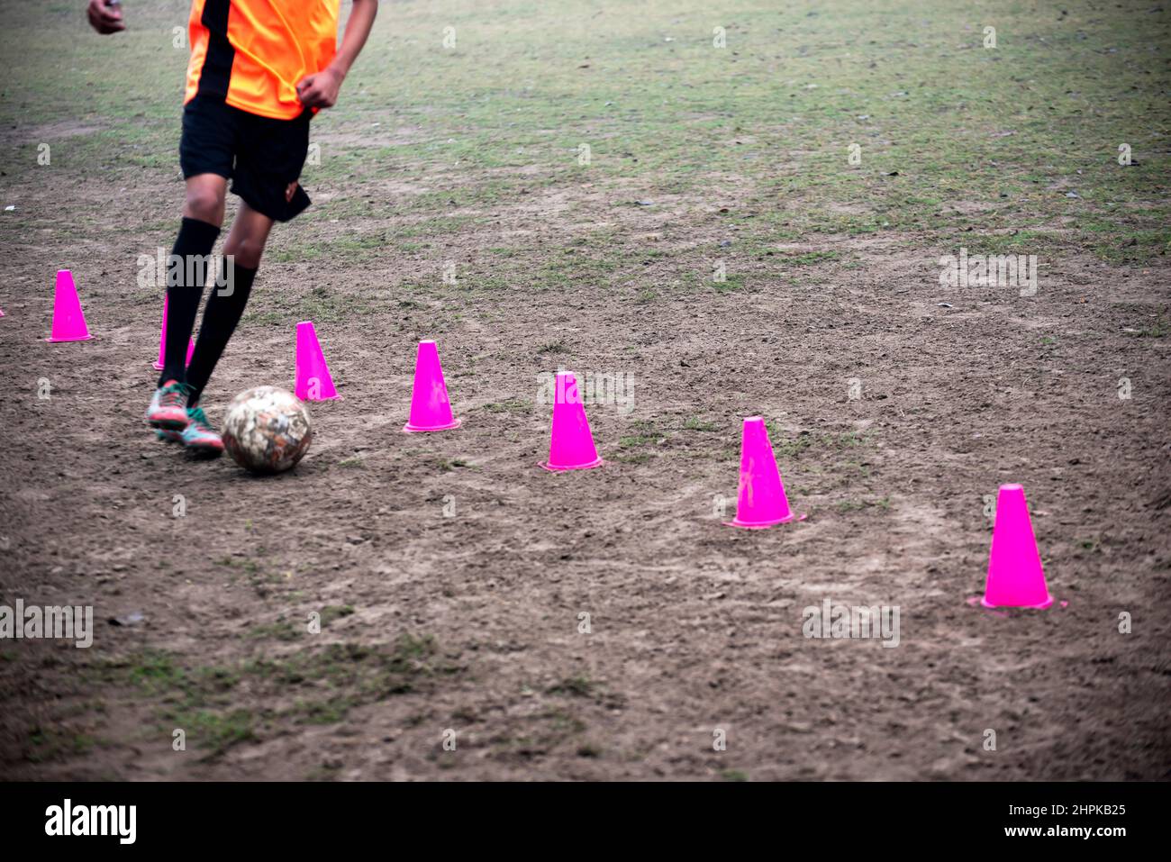 Footballer dribbling ball during training between cones. Young soccer ...