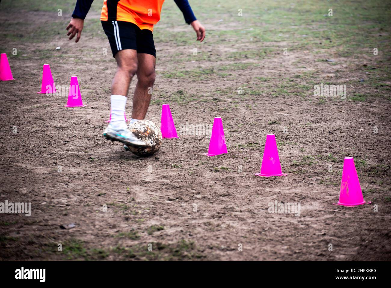 Footballer dribbling ball during training between cones. Young soccer ...