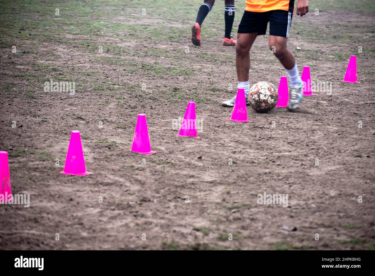 Footballer dribbling ball during training between cones. Young soccer ...