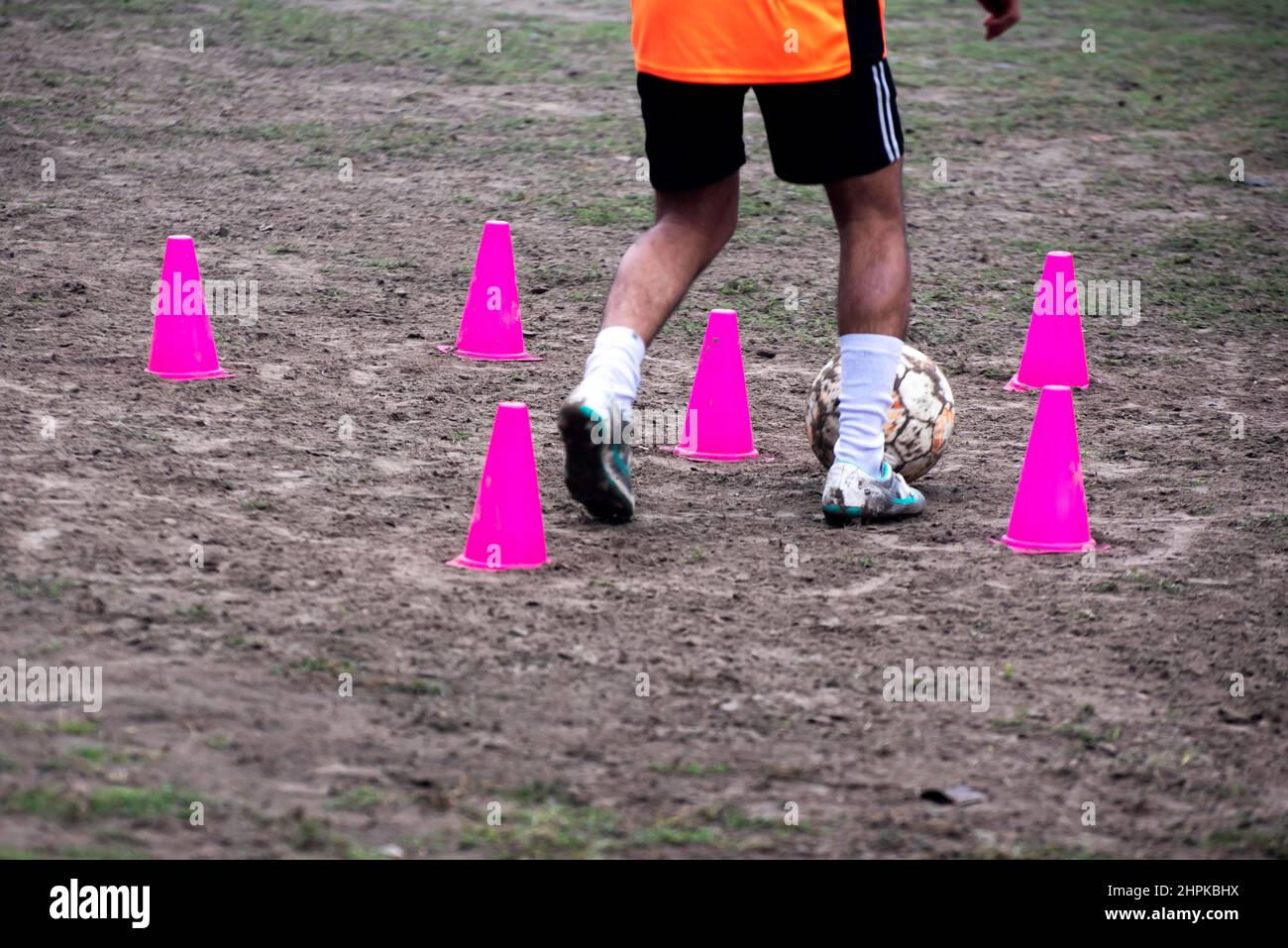 Footballer dribbling ball during training between cones. Young soccer ...