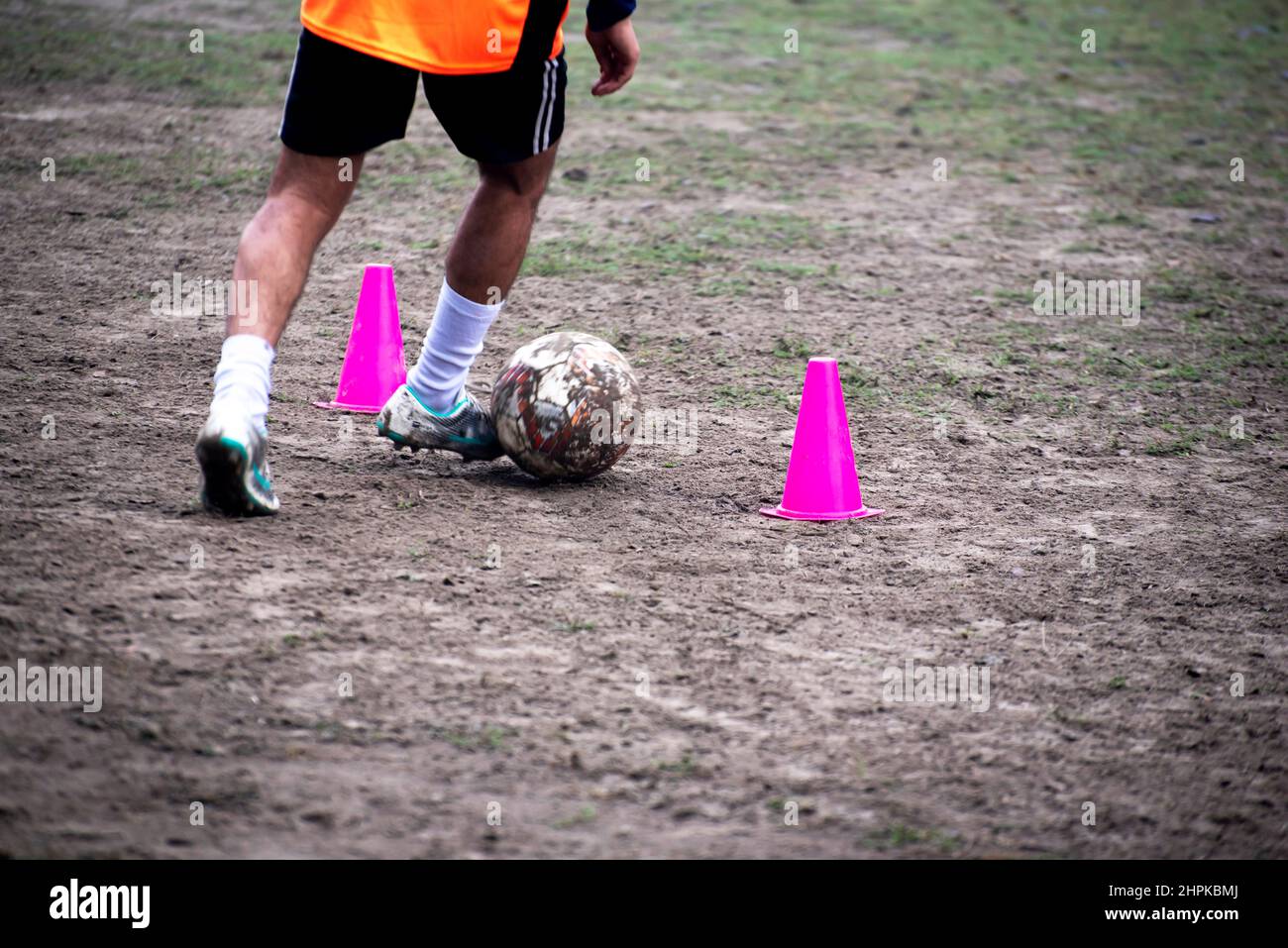 Footballer dribbling ball during training between cones. Young soccer ...