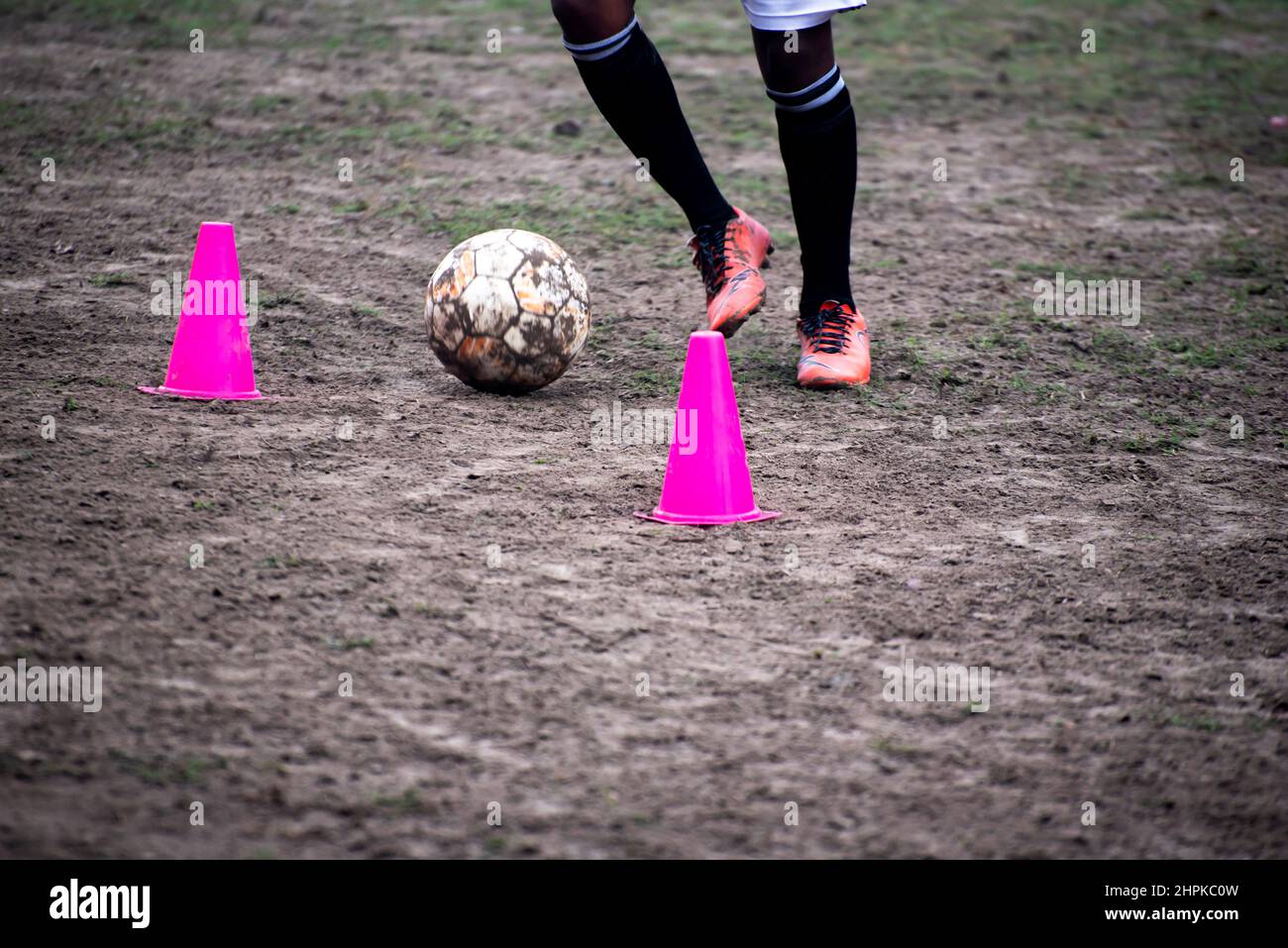 Footballer dribbling ball during training between cones. Young soccer ...