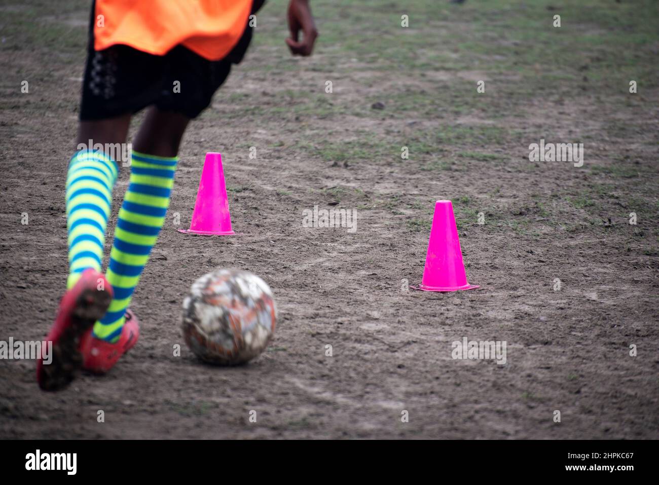 Footballer dribbling ball during training between cones. Young soccer ...