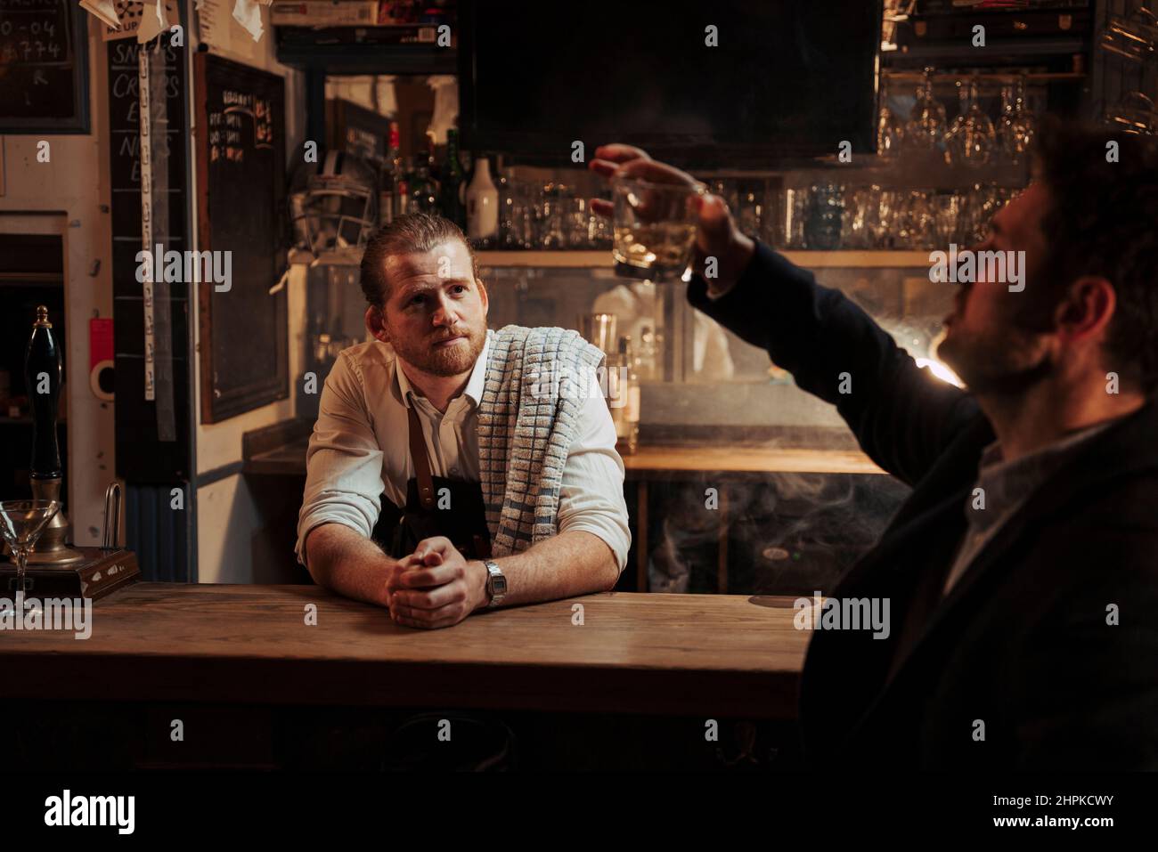 Caucasian bartender serving drunk customer drinking alone Stock Photo ...