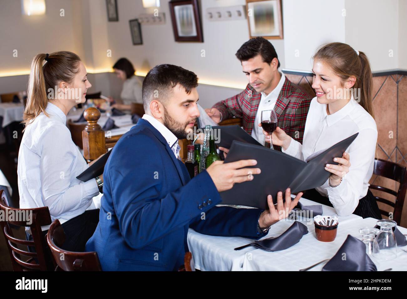 Сheerful friends choosing dishes out of menu card in restaurant Stock ...