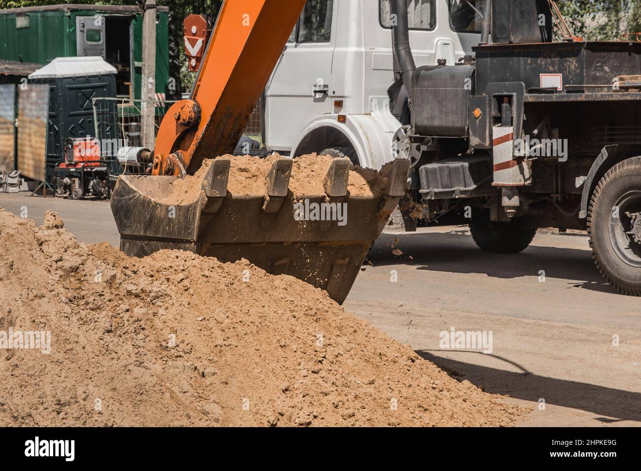 Excavation works. A tractor bucket unloads sand ground with a heavy ...