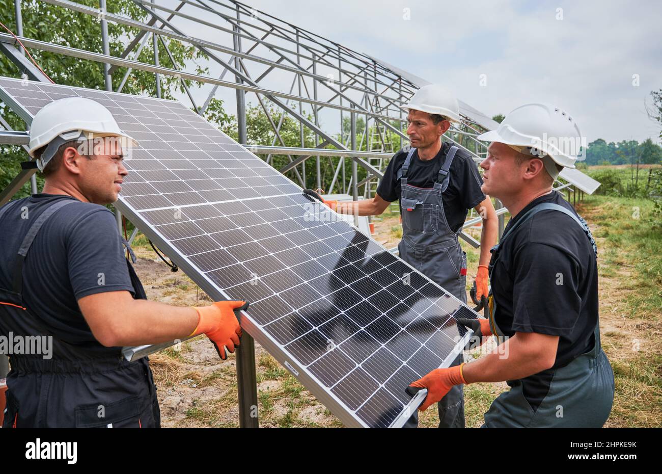Three men solar installers building photovoltaic solar panel system ...