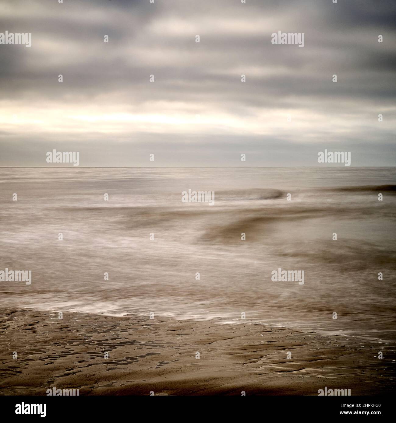 Tide coming in onto beach at nightfall Stock Photo - Alamy