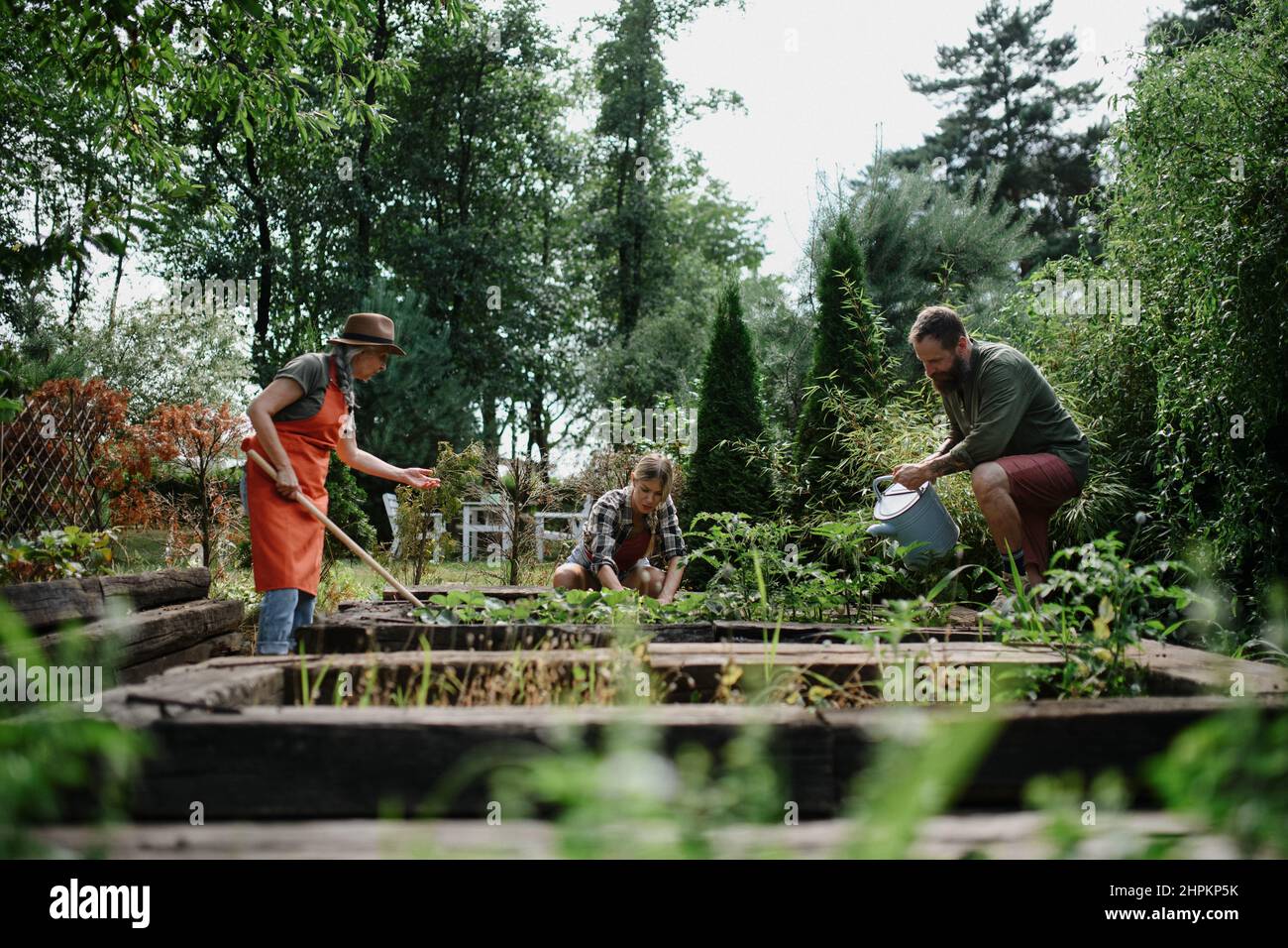 Happy young and old farmers working with garden tools outdoors at a ...