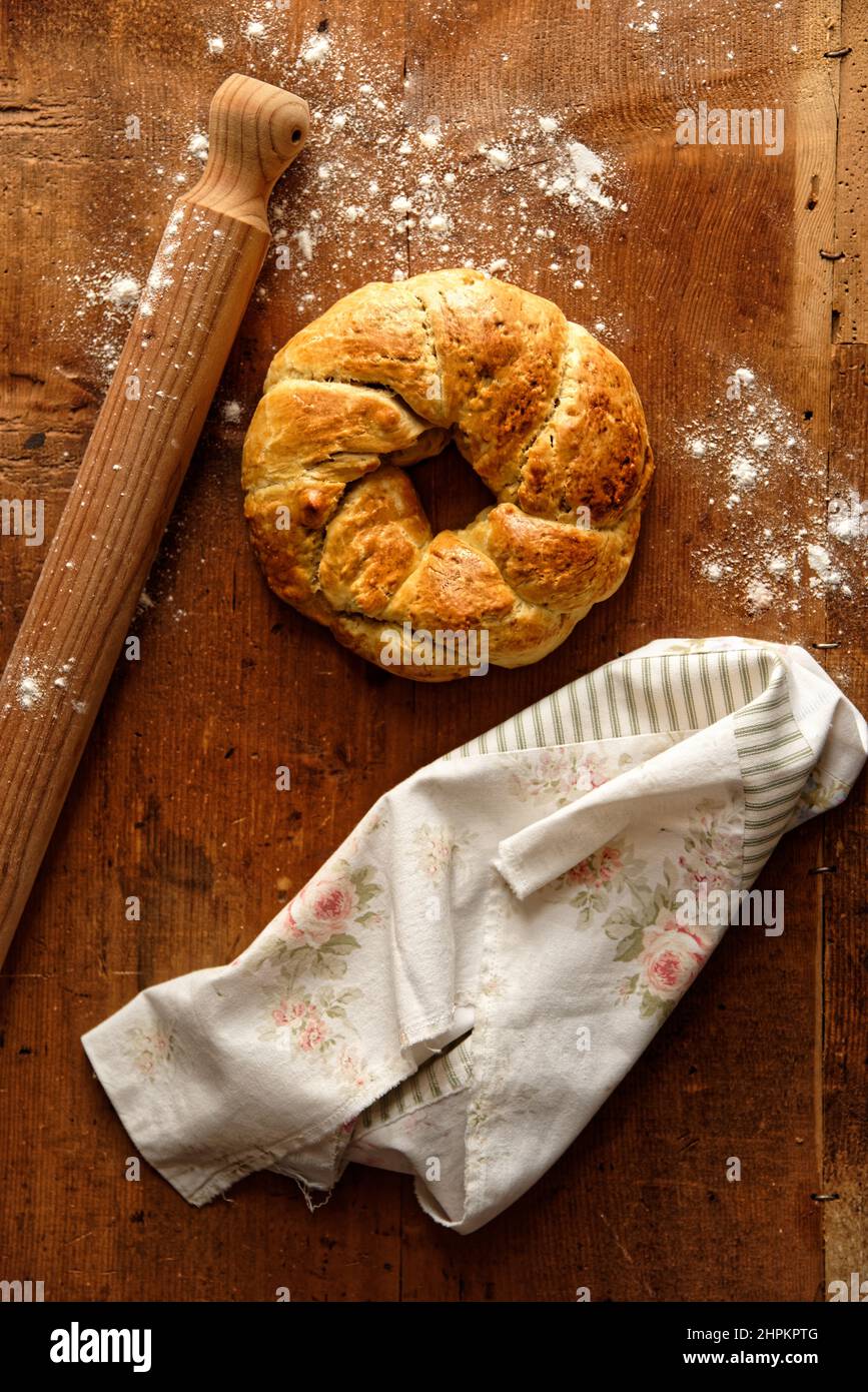 Homemade ring shaped bread in wood lay with rolling pin, some flour ...