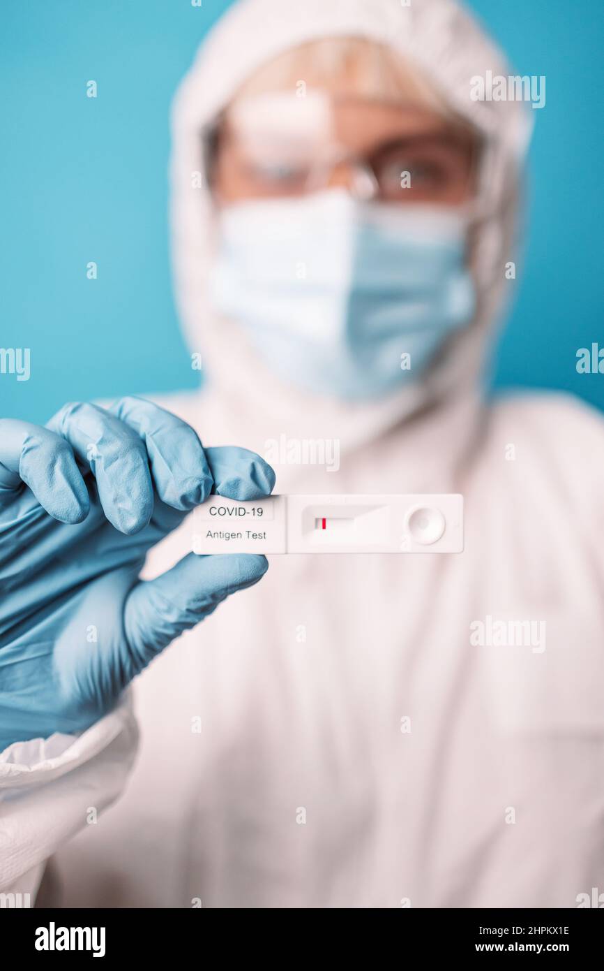 Doctor in blue gloves holding rapid antigen test kit during swab COVID ...