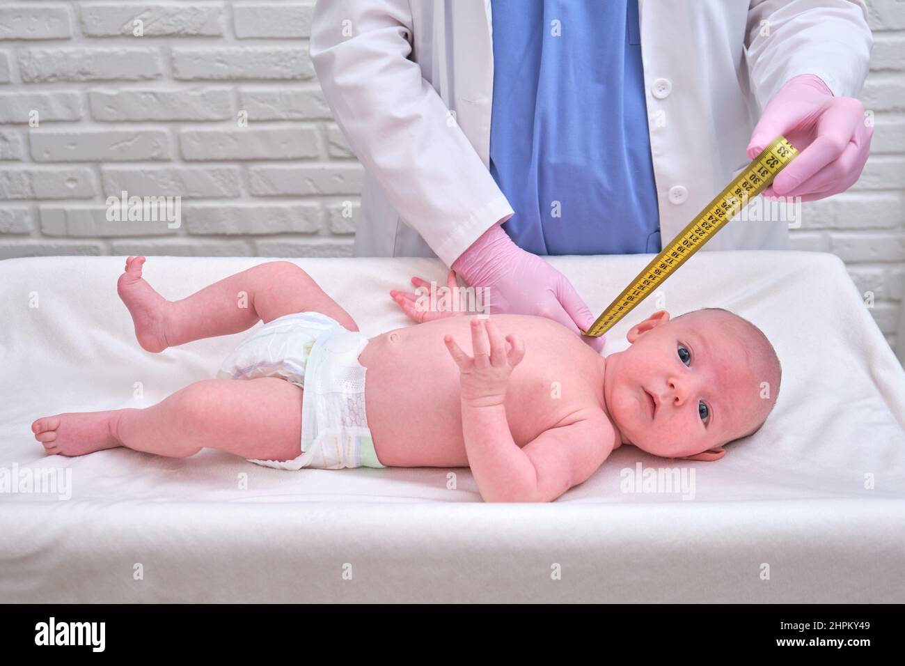 Doctor measures the growth of a newborn baby. A nurse in uniform checks ...