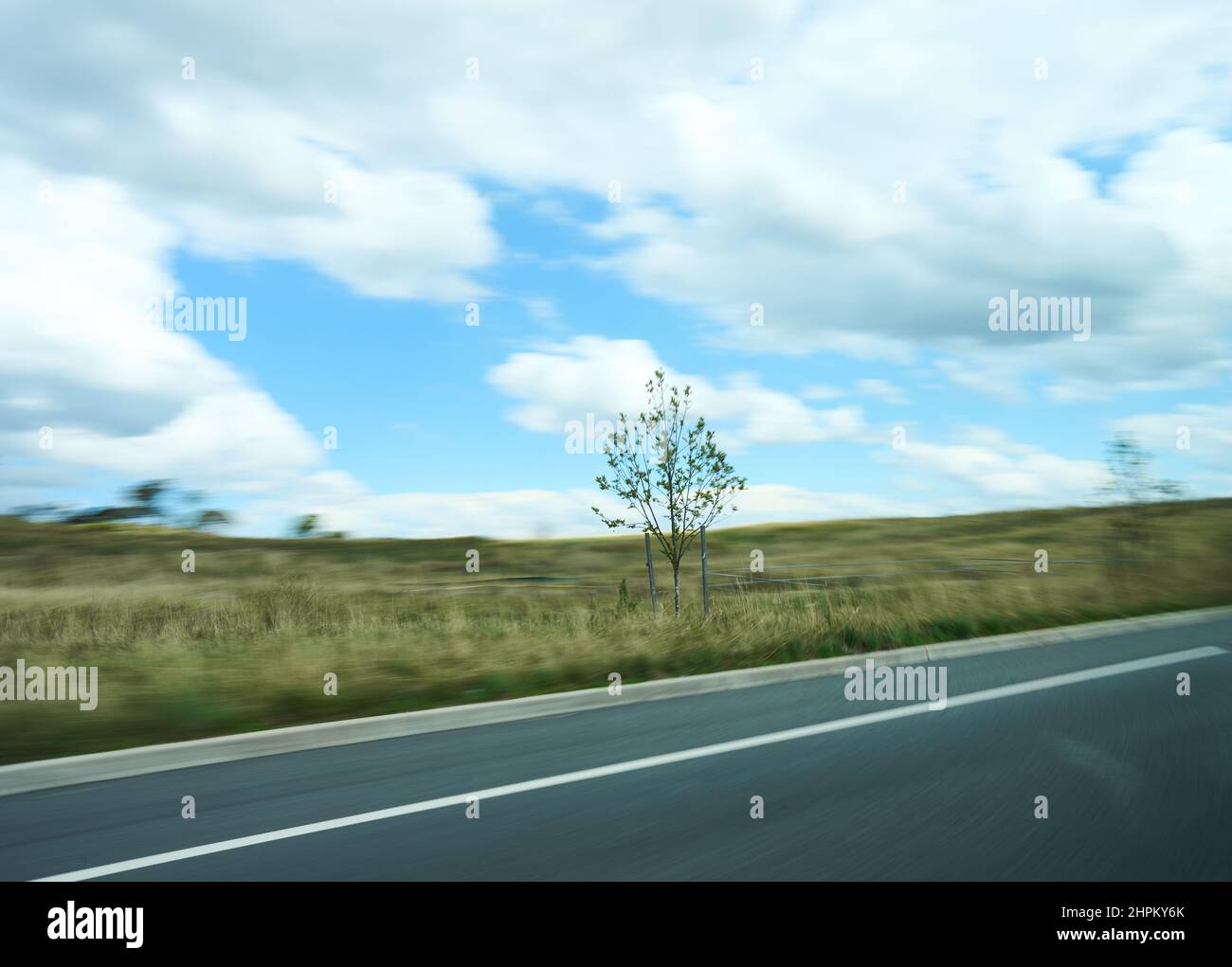 Scenic view of a field next to an asphalt road on cloudy sky background ...