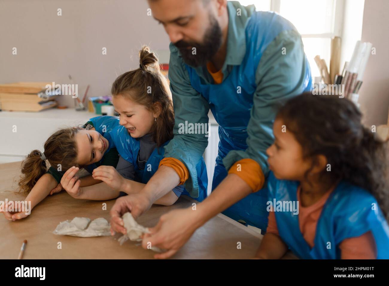 Group of little kids with teacher working with pottery clay during ...